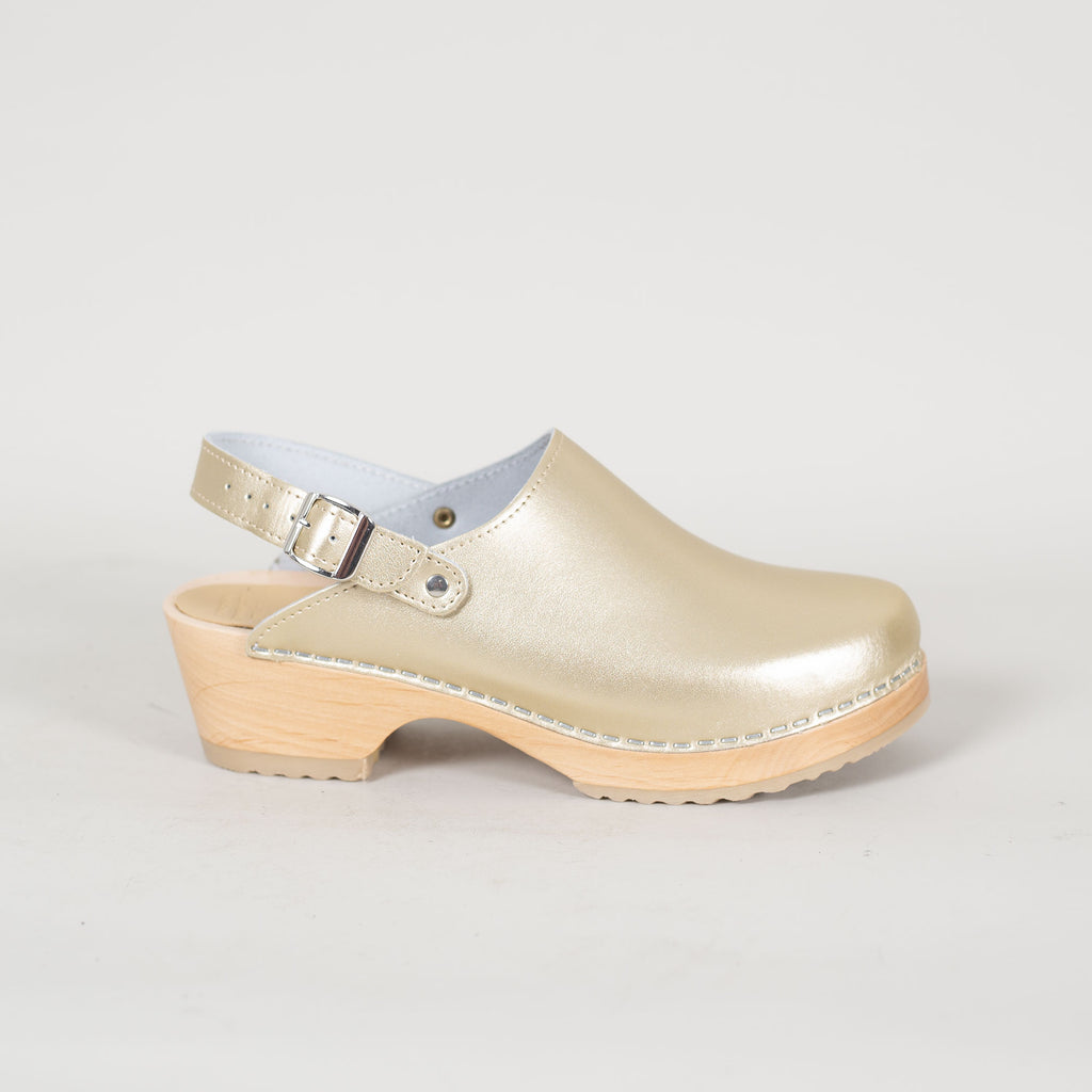 Austin clogs in light gold metallic leather on a natural wooden bottom